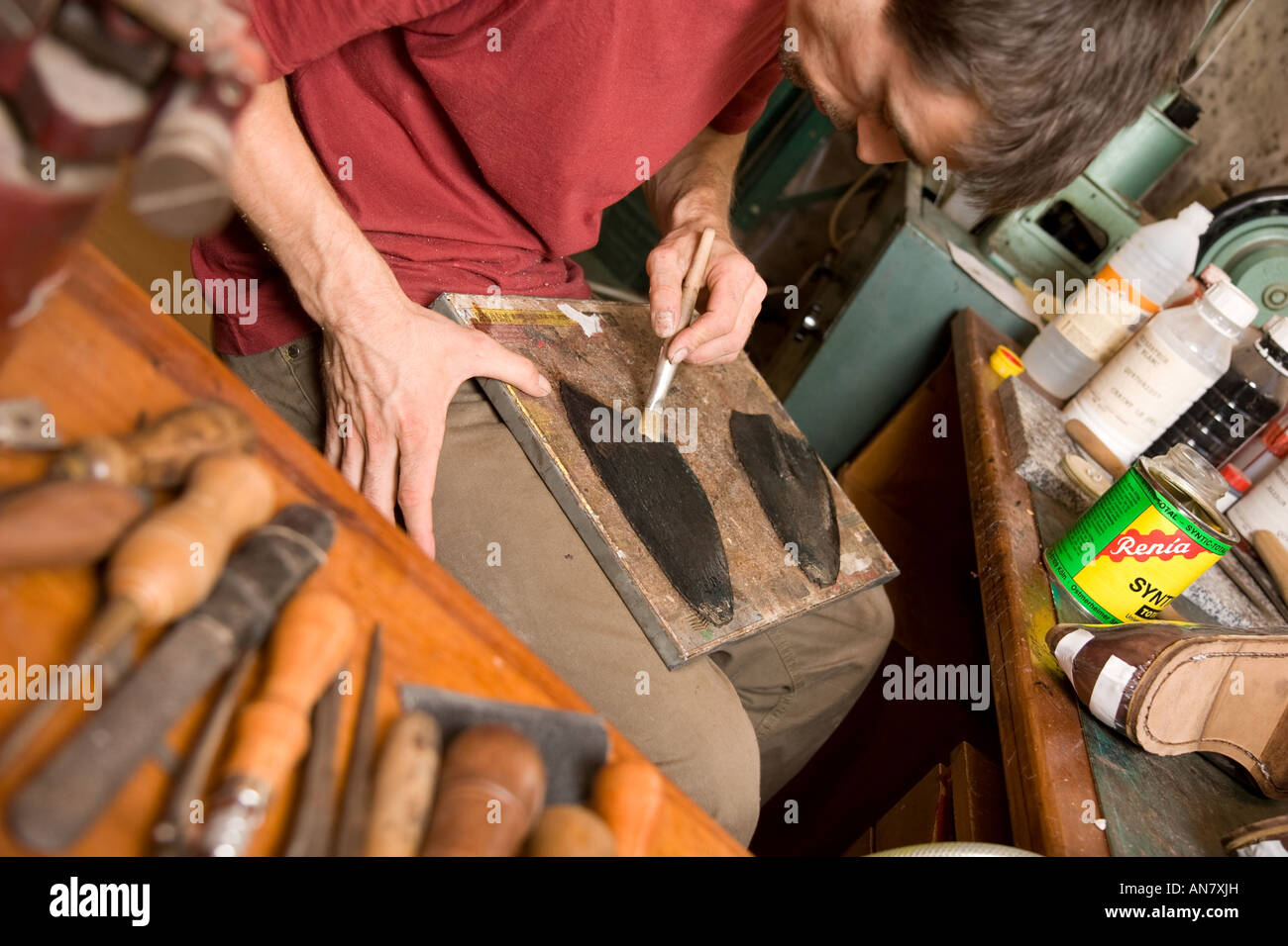 A shoe being made by a traditional shoe maker Glue is being applied to ...