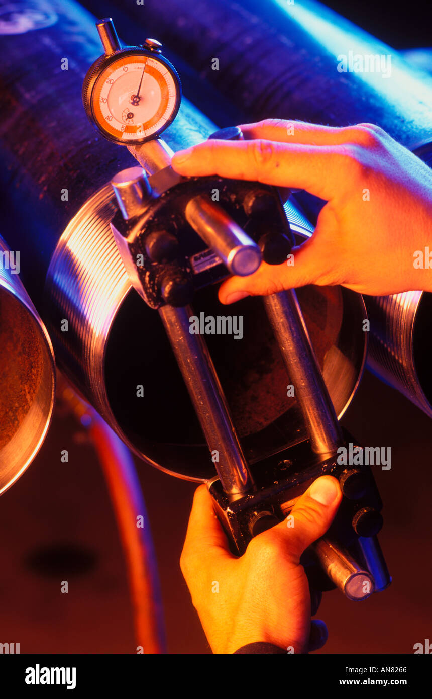 Worker using calibration device to check the width of oil drilling pipe ...