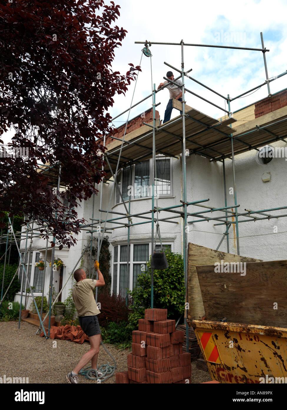 Builders Using Hoist to move Tiles to the Roof Stock Photo - Alamy