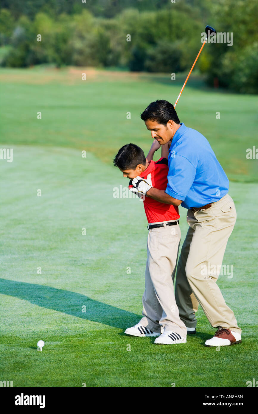 Hispanic father helping son play golf Stock Photo - Alamy