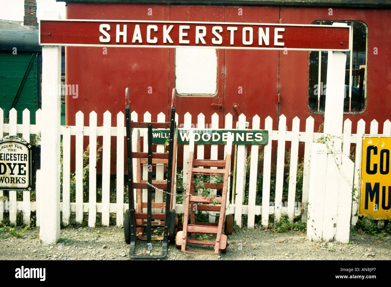Sign in front of a red painted station building Station name is ...