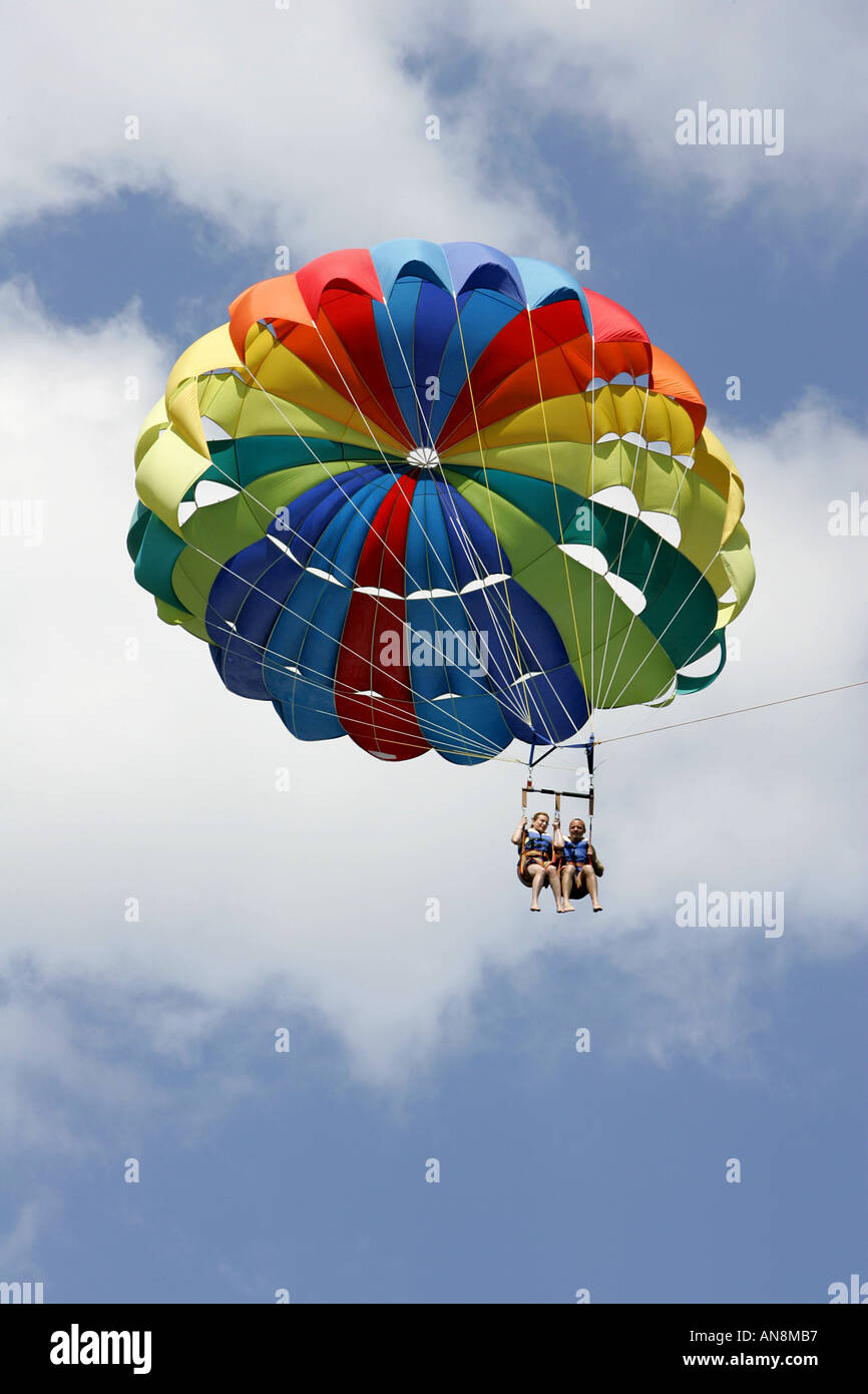 A tandem parachute paragliding behind a beach parasailing rainbow red ...