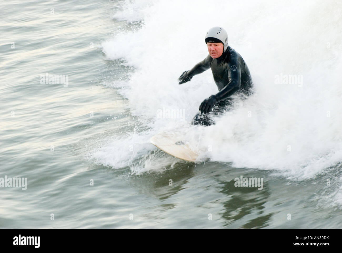A colour landscape image of a middle aged surfer riding a wave in the ...