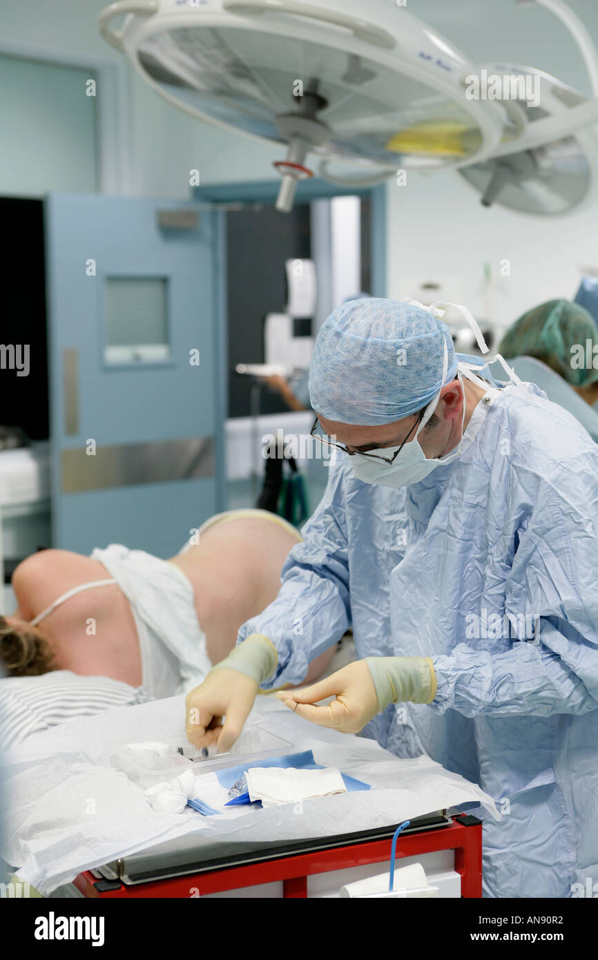 A woman receiving an injection into the spine in theatre before ...