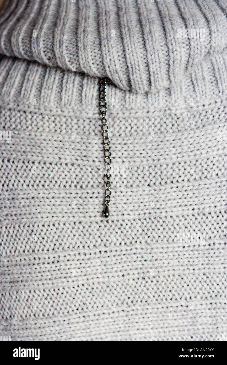 Thin chain from necklace draped over back of woman's woolen top Stock ...