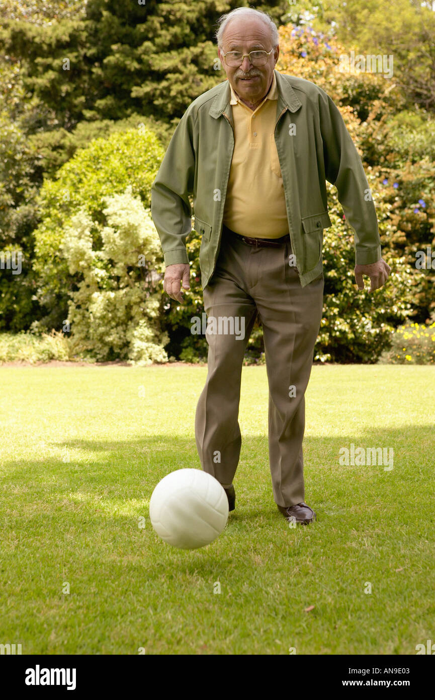 Senior man kicking football Stock Photo - Alamy