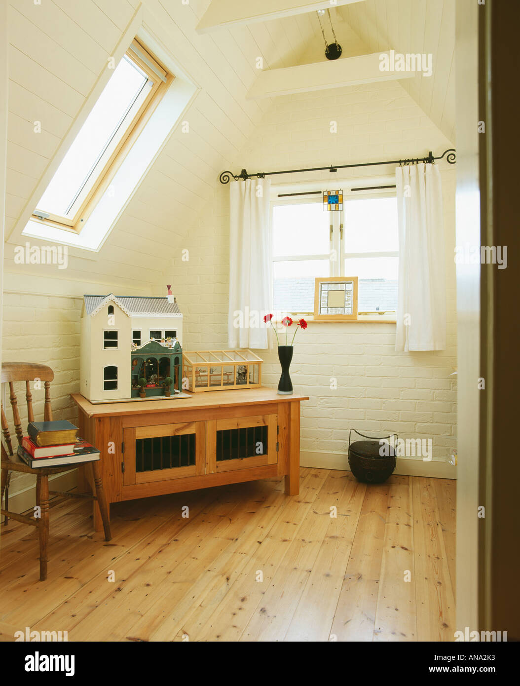Doll's house on wooden chest in white attic conversion with Velux ...