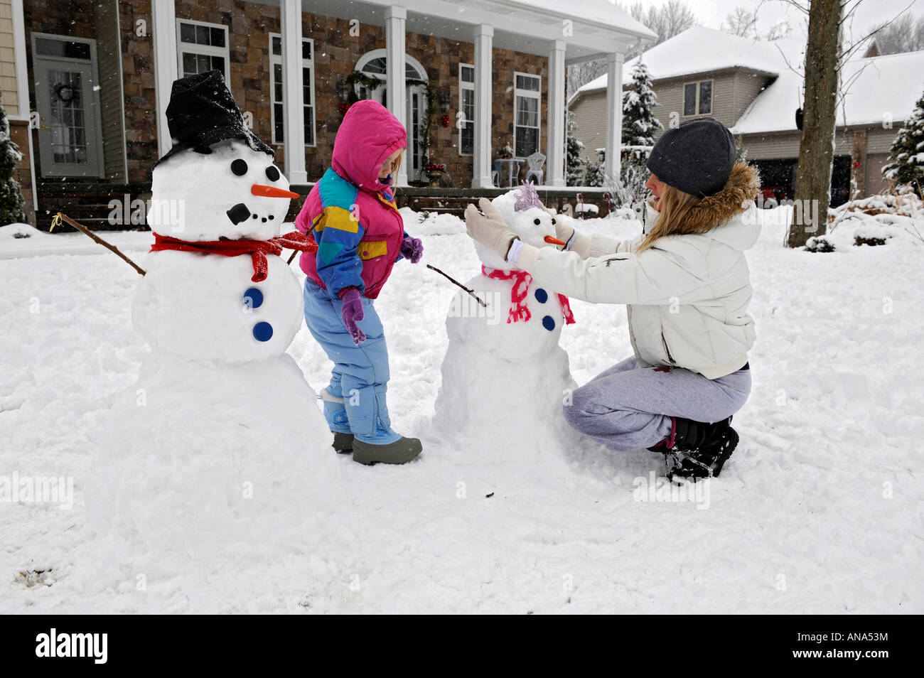 Children build snowman with mother after a winter snowfall Stock Photo ...