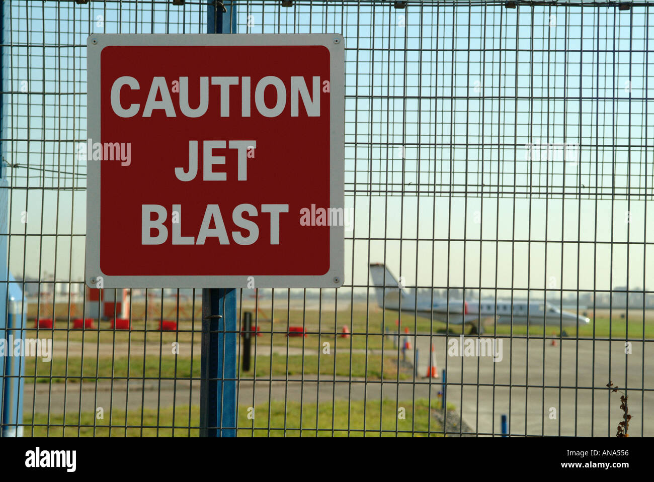 Warning sign on airport fence with executive jet in the background ...