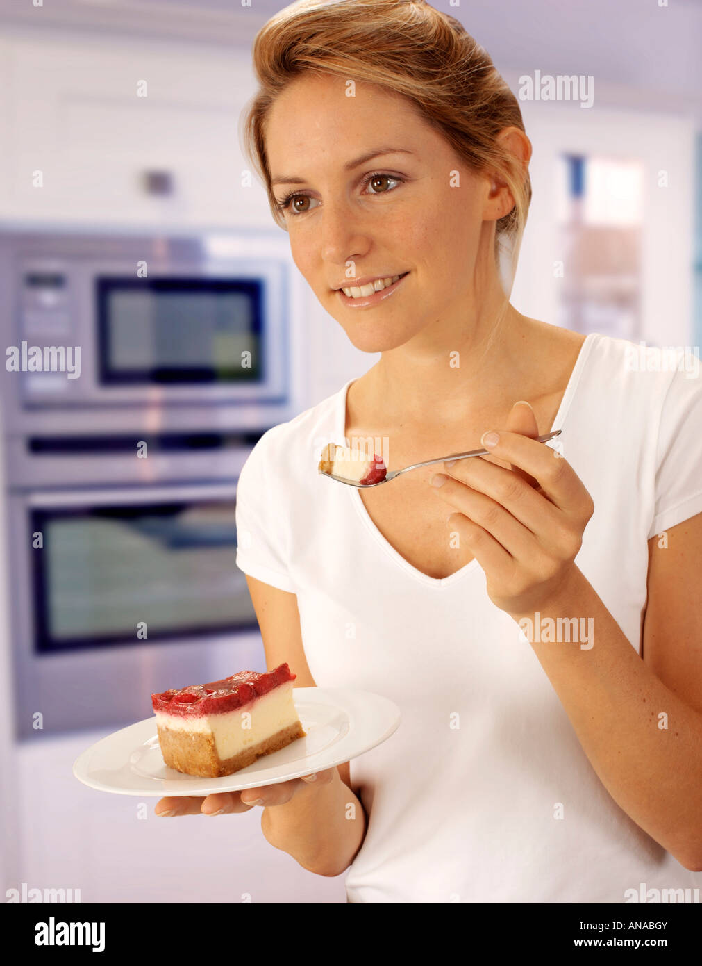 WOMAN IN KITCHEN EATING CHEESECAKE Stock Photo - Alamy