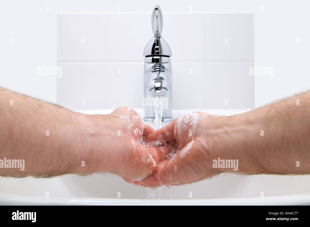 Man washing his hands with soap under running water in a white hand ...