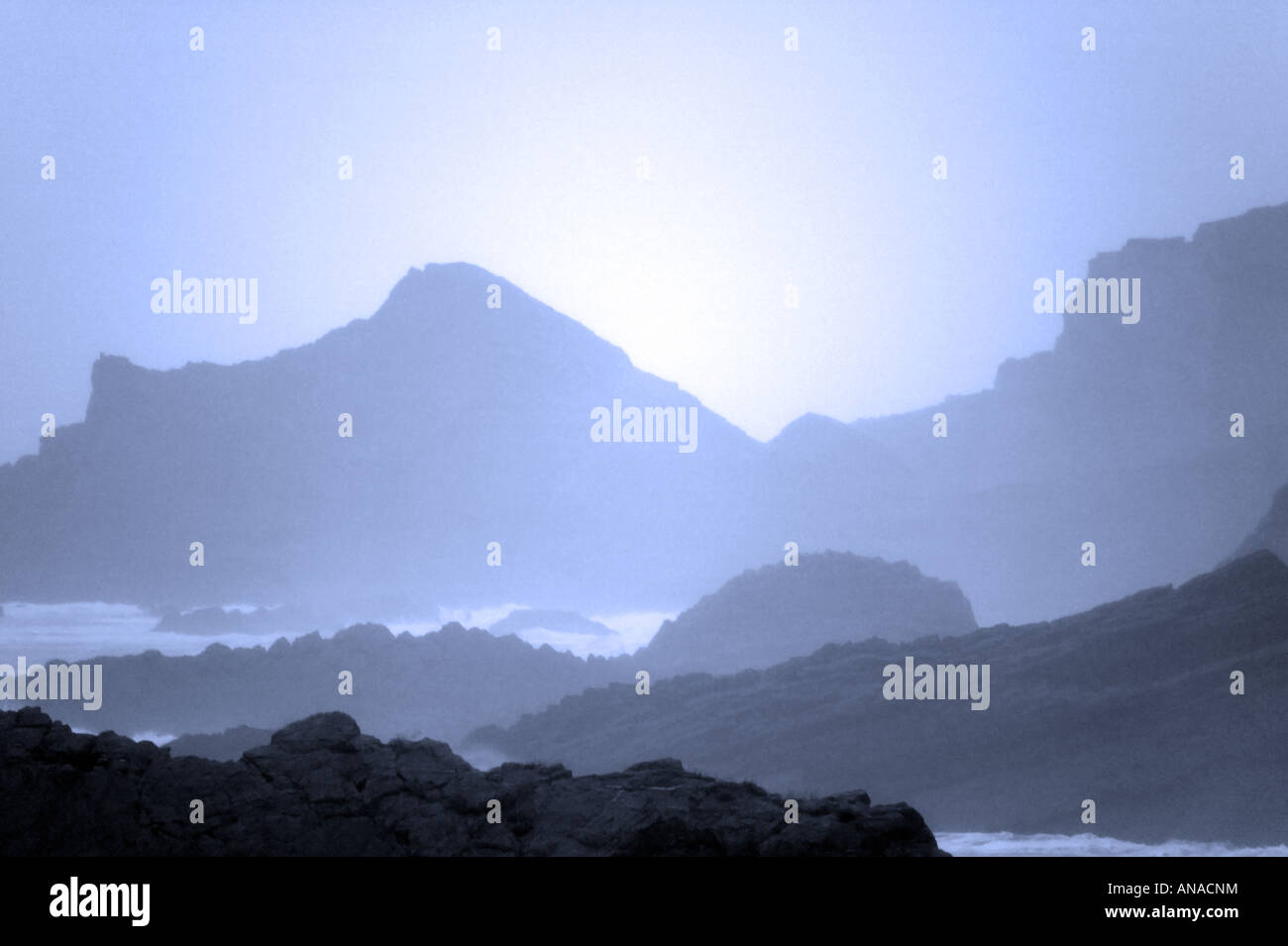 Sea fog on a rocky coastline grainy image as a result of natural light ...
