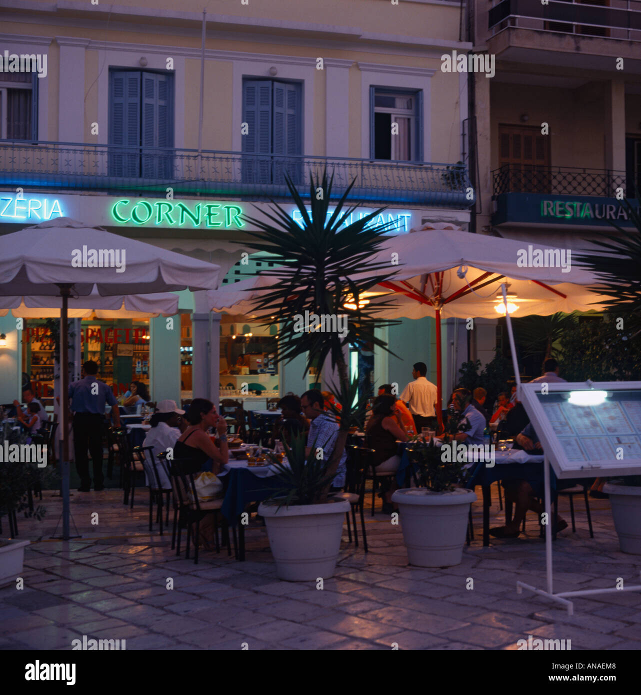 People eating out at covered tables in Platia Agiu Square at sunset in ...