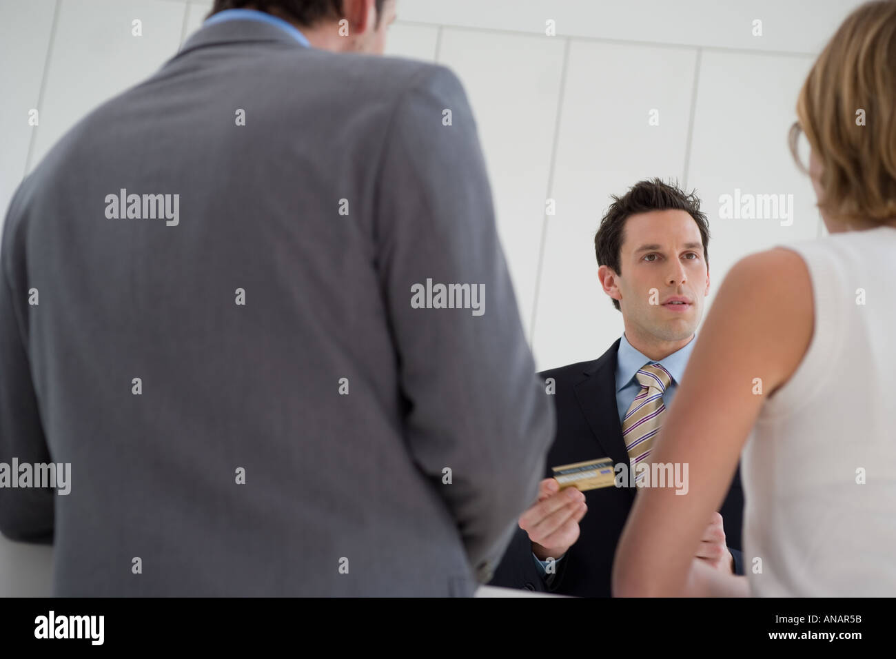 rear view of man and woman paying with credit card at reception desk ...