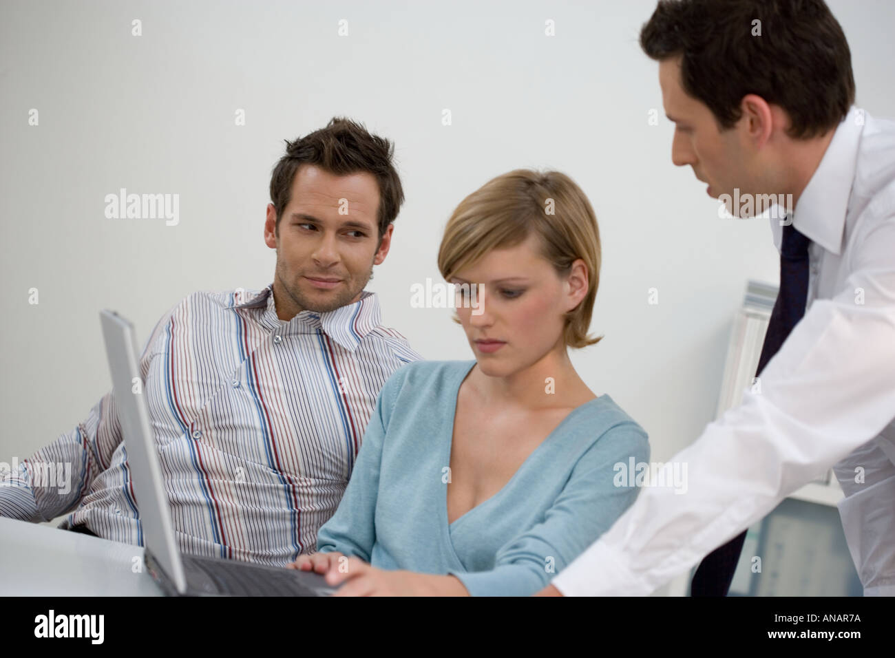 businesswoman being helped by colleagues sitting around laptop computer ...