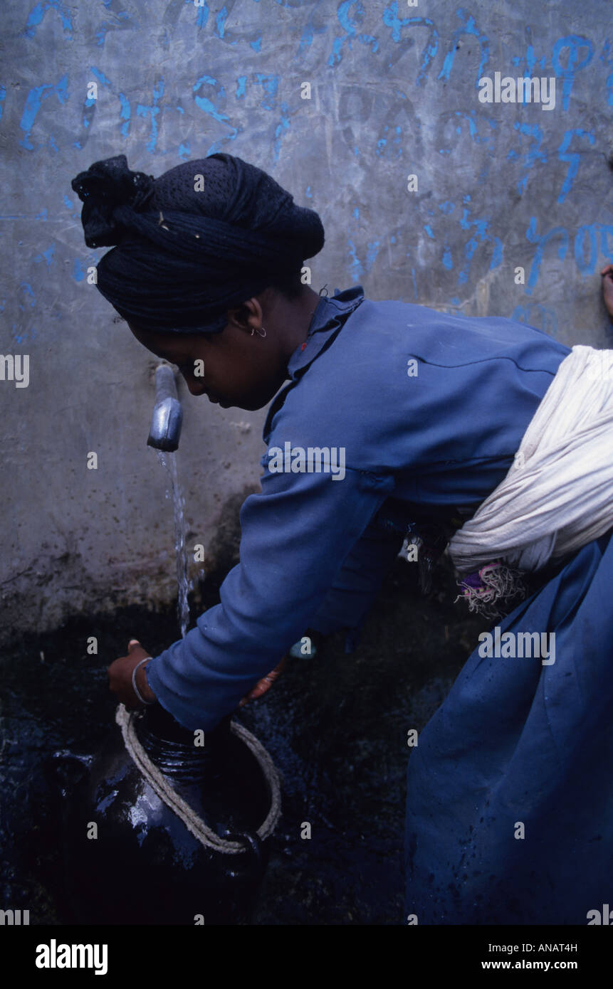A young girl filling up an amphora of water from a water point in the ...