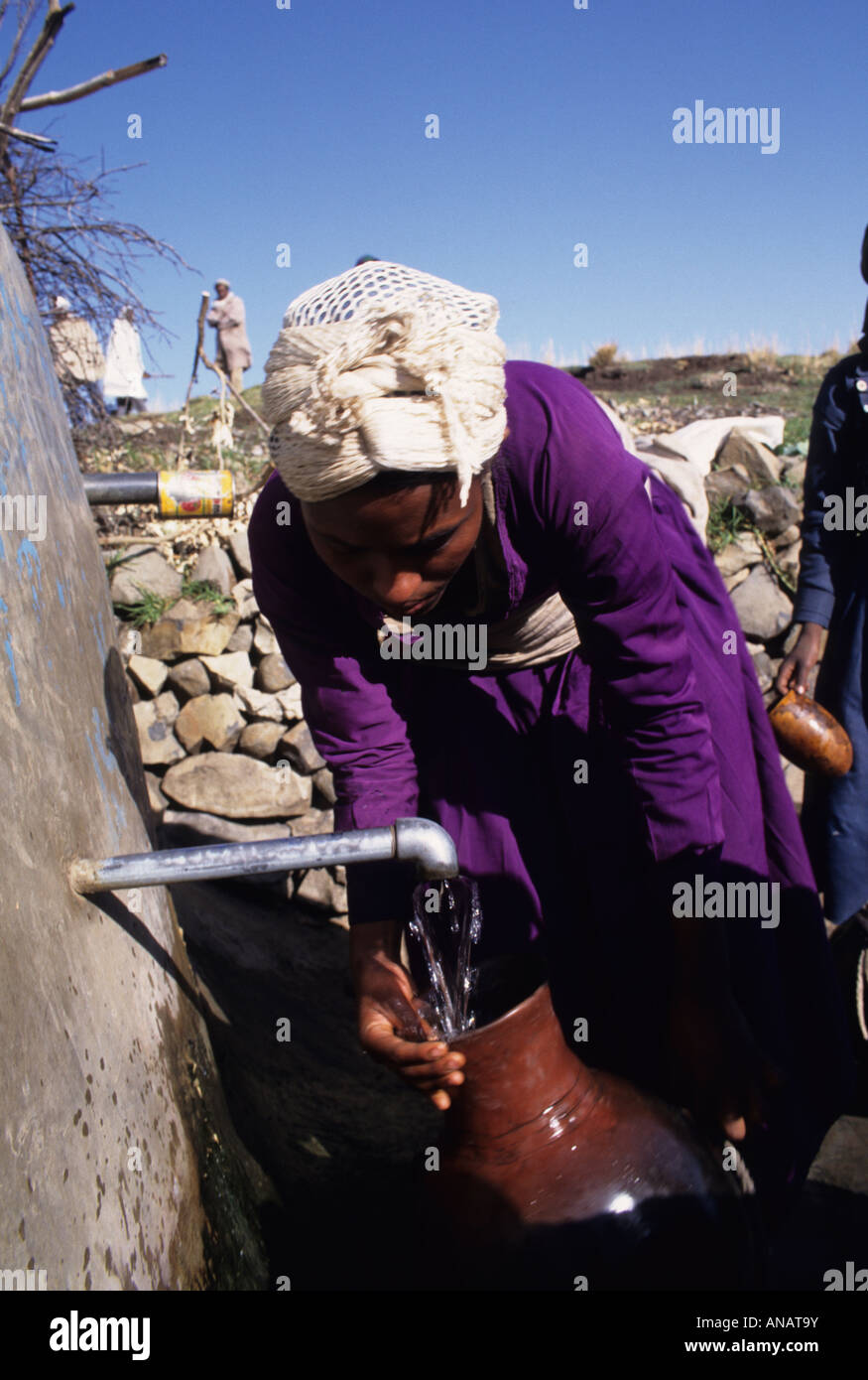 Girl filling up an amphora of water from a water point in the highlands ...
