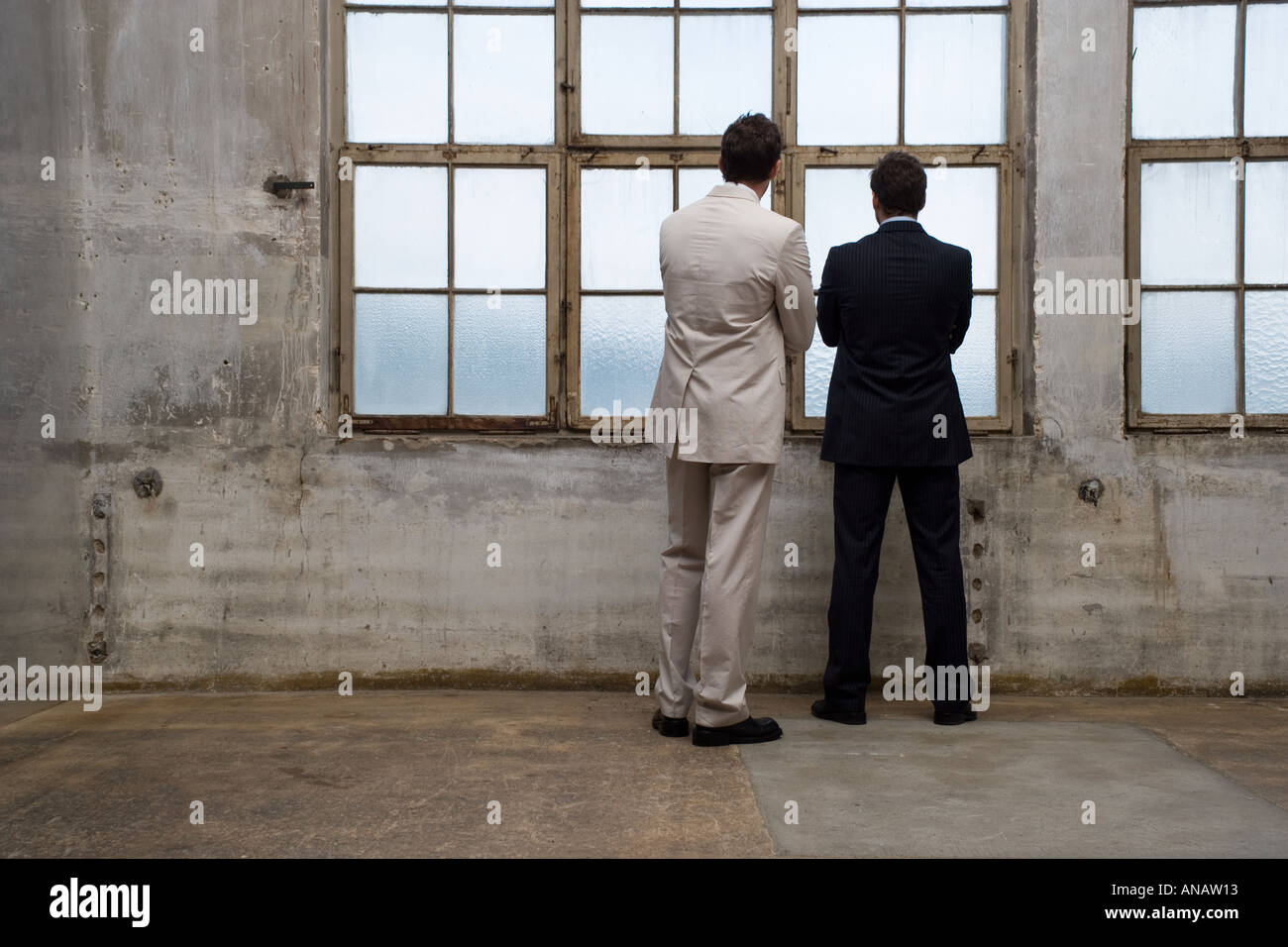 two businessmen looking out of window in empty building Stock Photo - Alamy