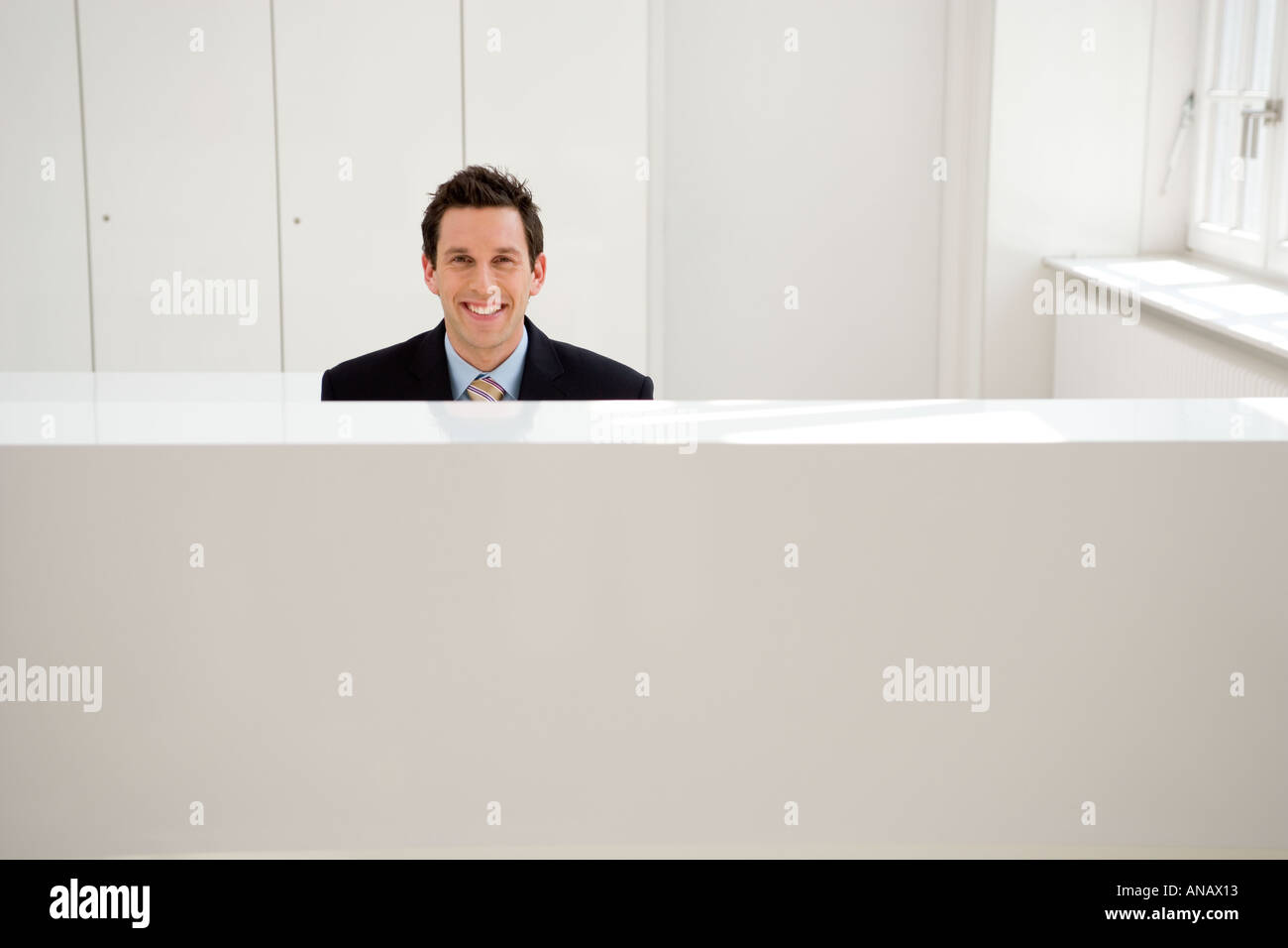 smiling receptionist behind his welcome desk in lobby Stock Photo - Alamy
