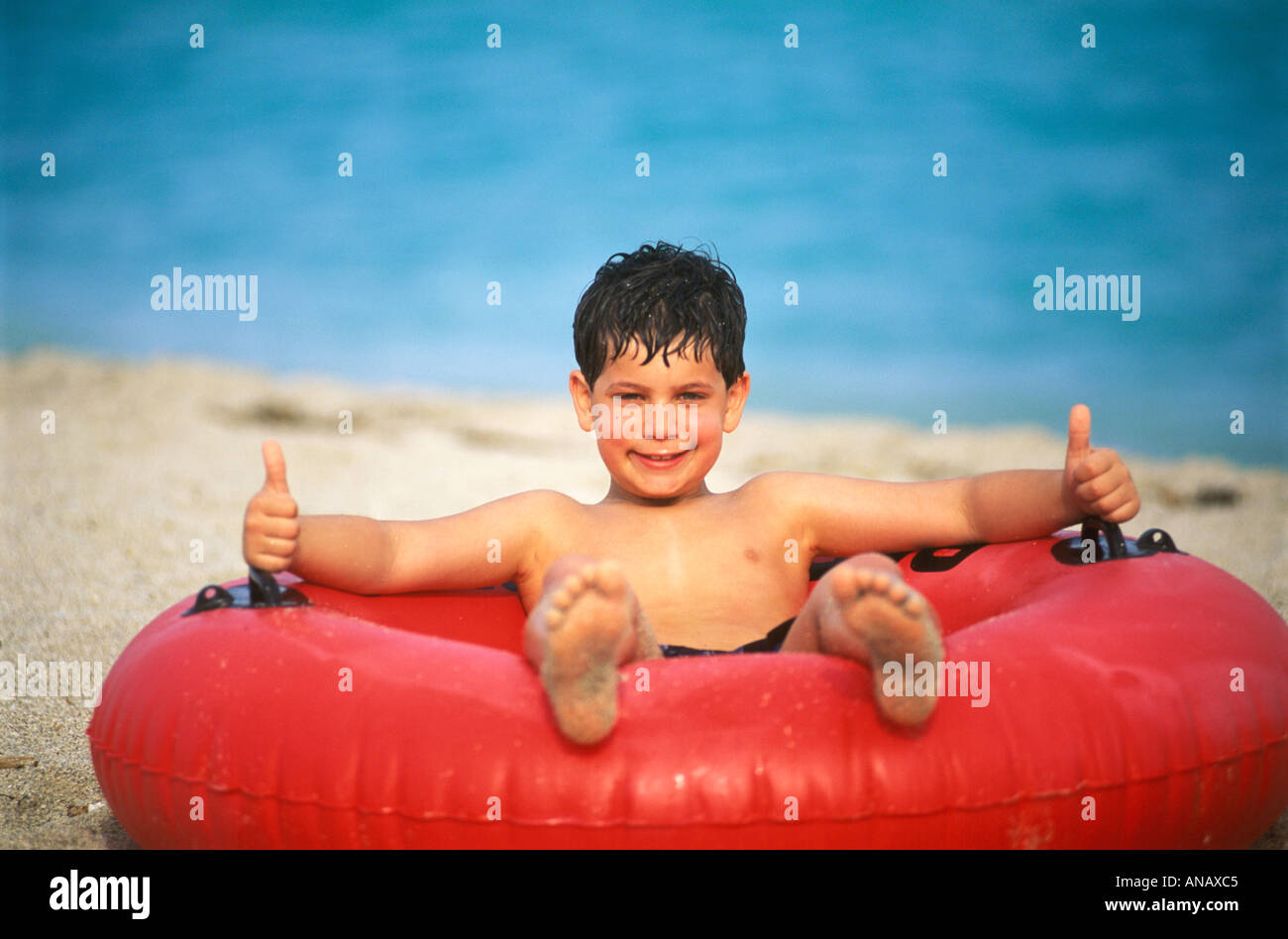 Boy on inner tube on beach Stock Photo - Alamy