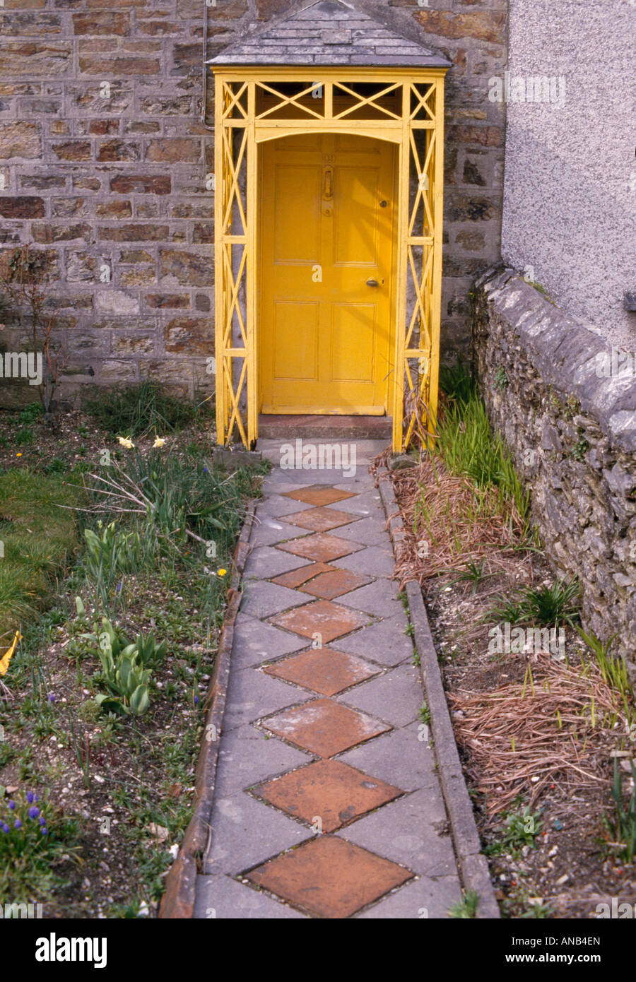 Diamond patterned paved path to yellow front door with ornate wooden ...