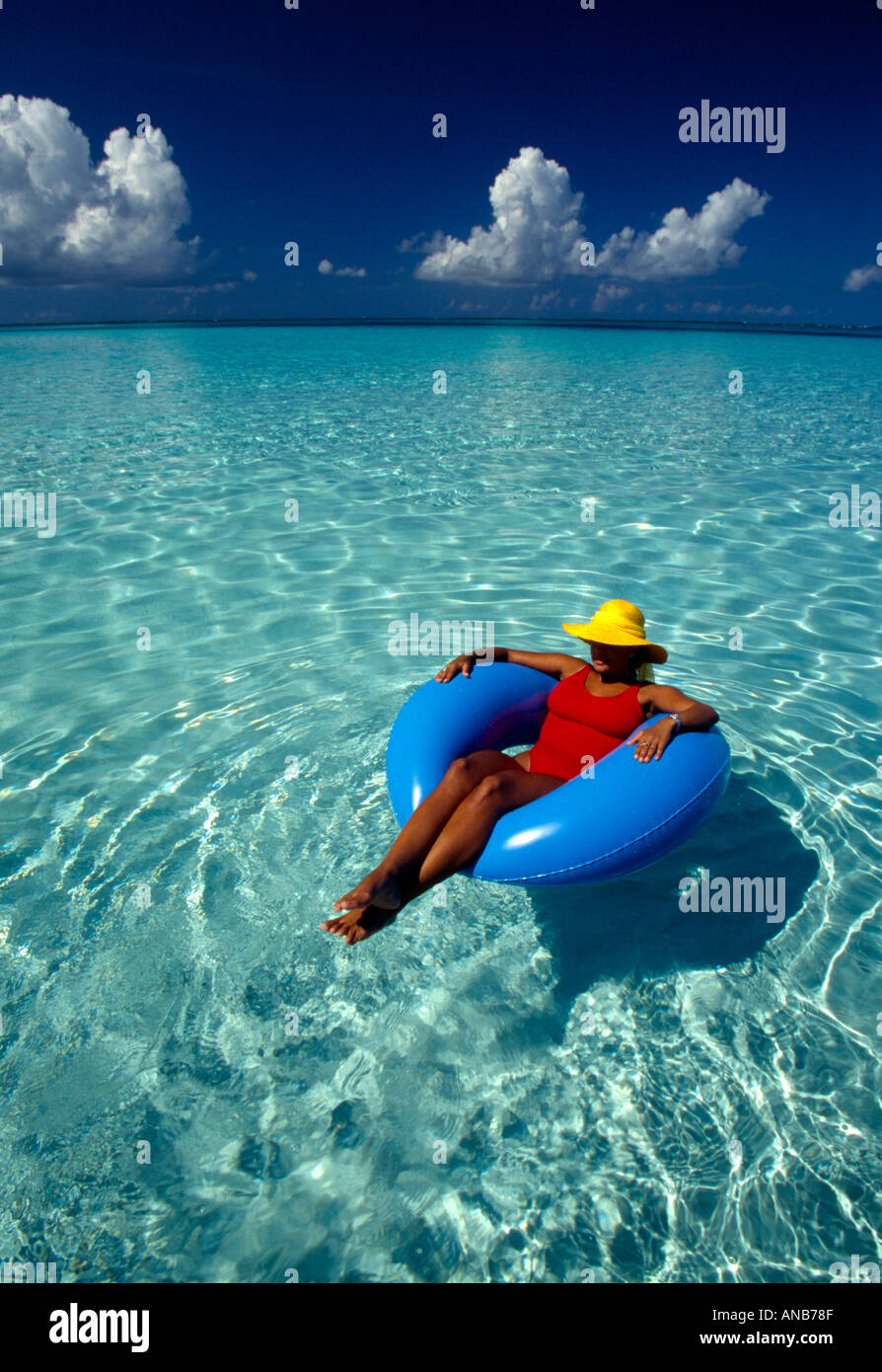 Grand Cayman Sandbar Woman in red suit and yellow hat floats on blue ...