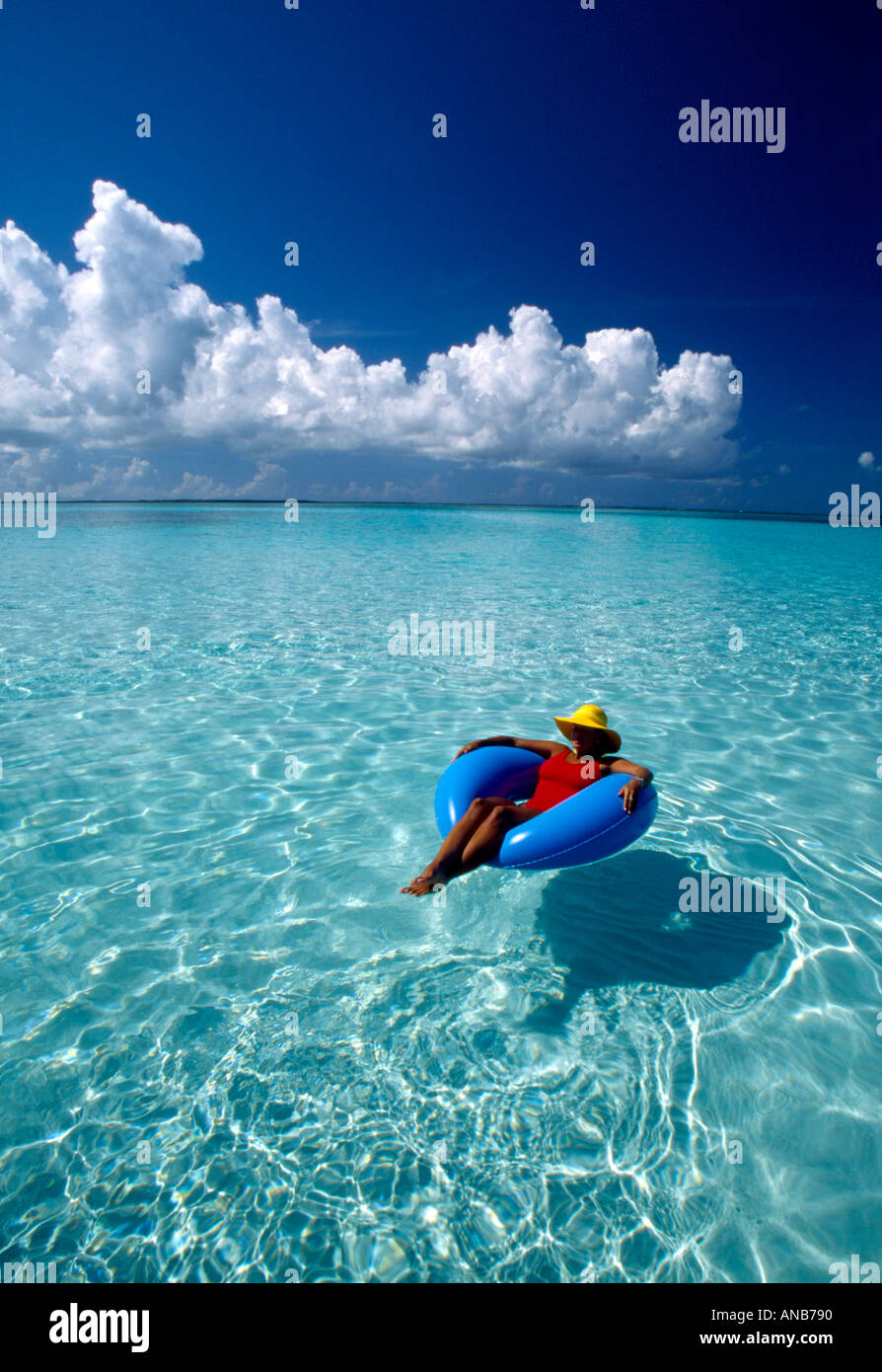 Grand Cayman Sandbar Woman in red suit and yellow hat floats on blue ...