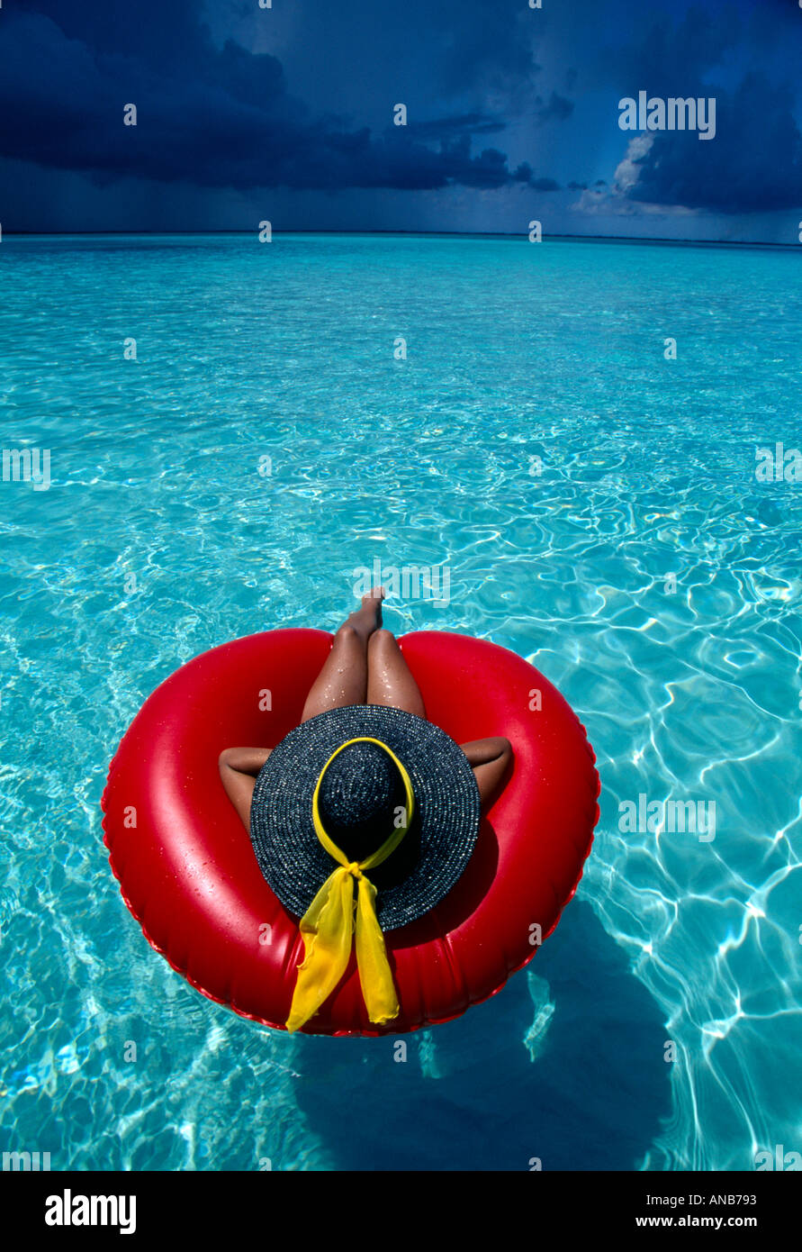 Grand Cayman Sandbar Woman in black hat floats in a red inter tube over ...