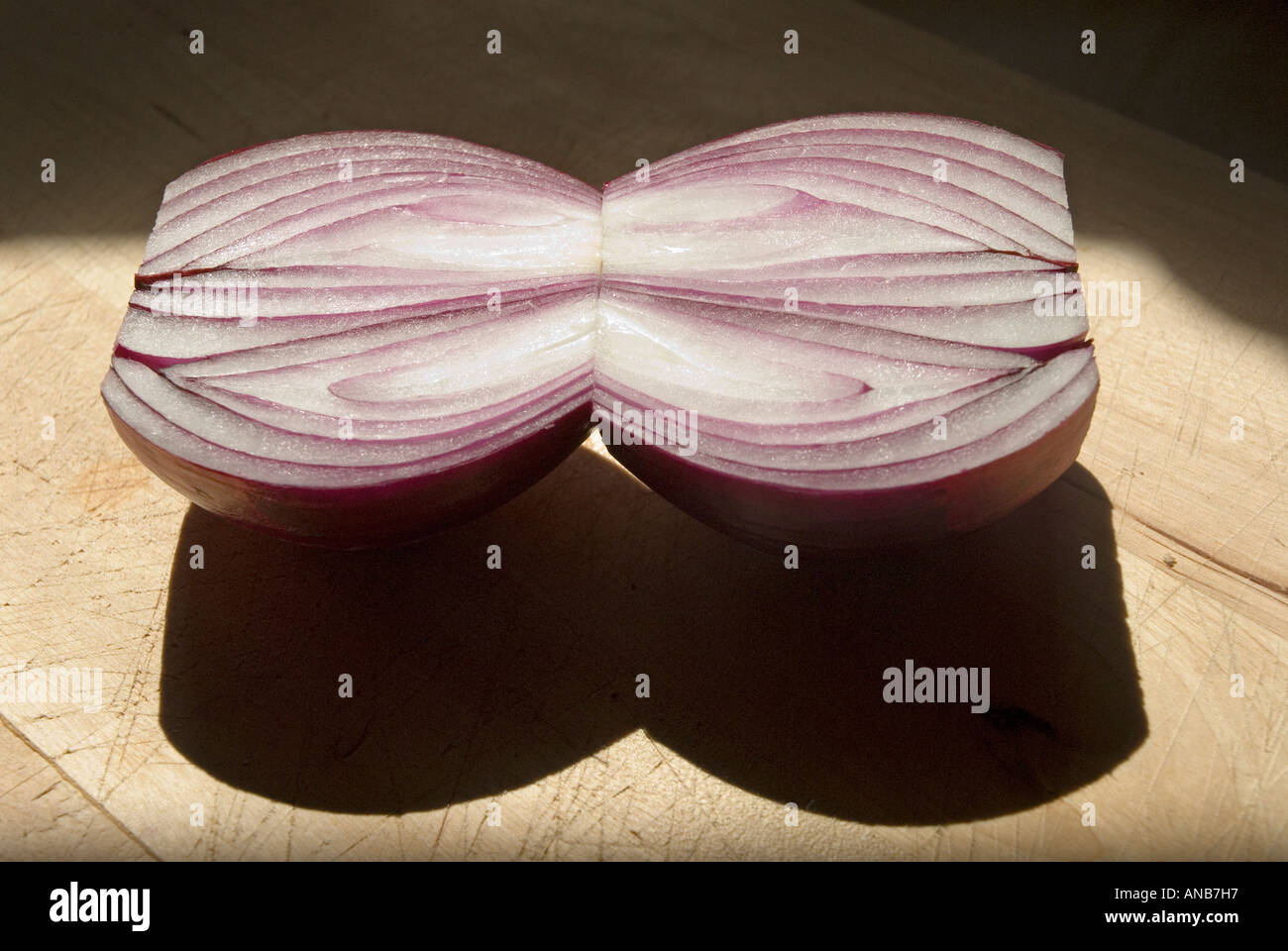 A red onion cut in half on a chopping board Stock Photo - Alamy