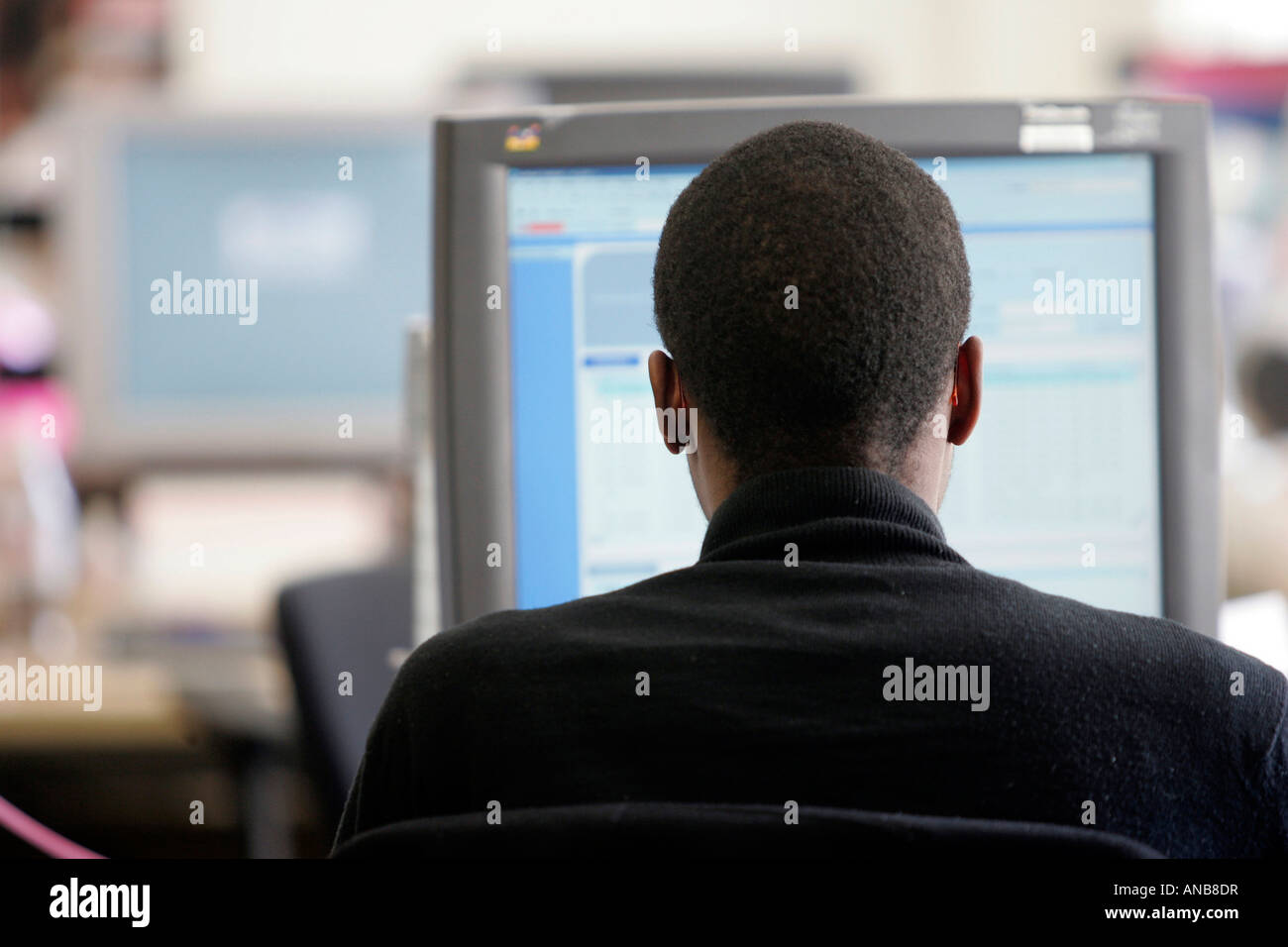 A man sitting at an office computer, seen from behind Stock Photo - Alamy