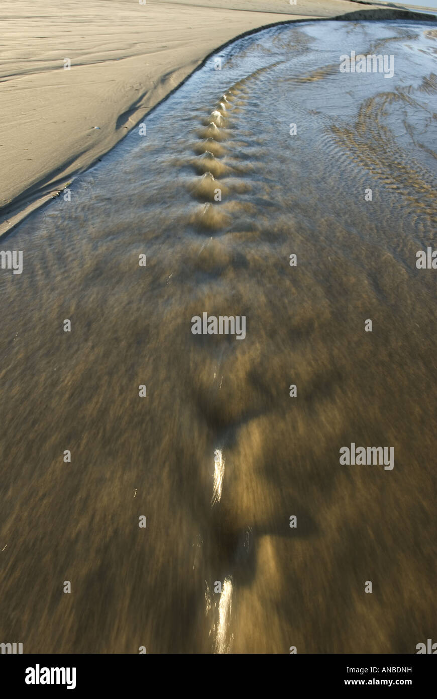 The change of the tide shapes the sand at the beach during an early ...