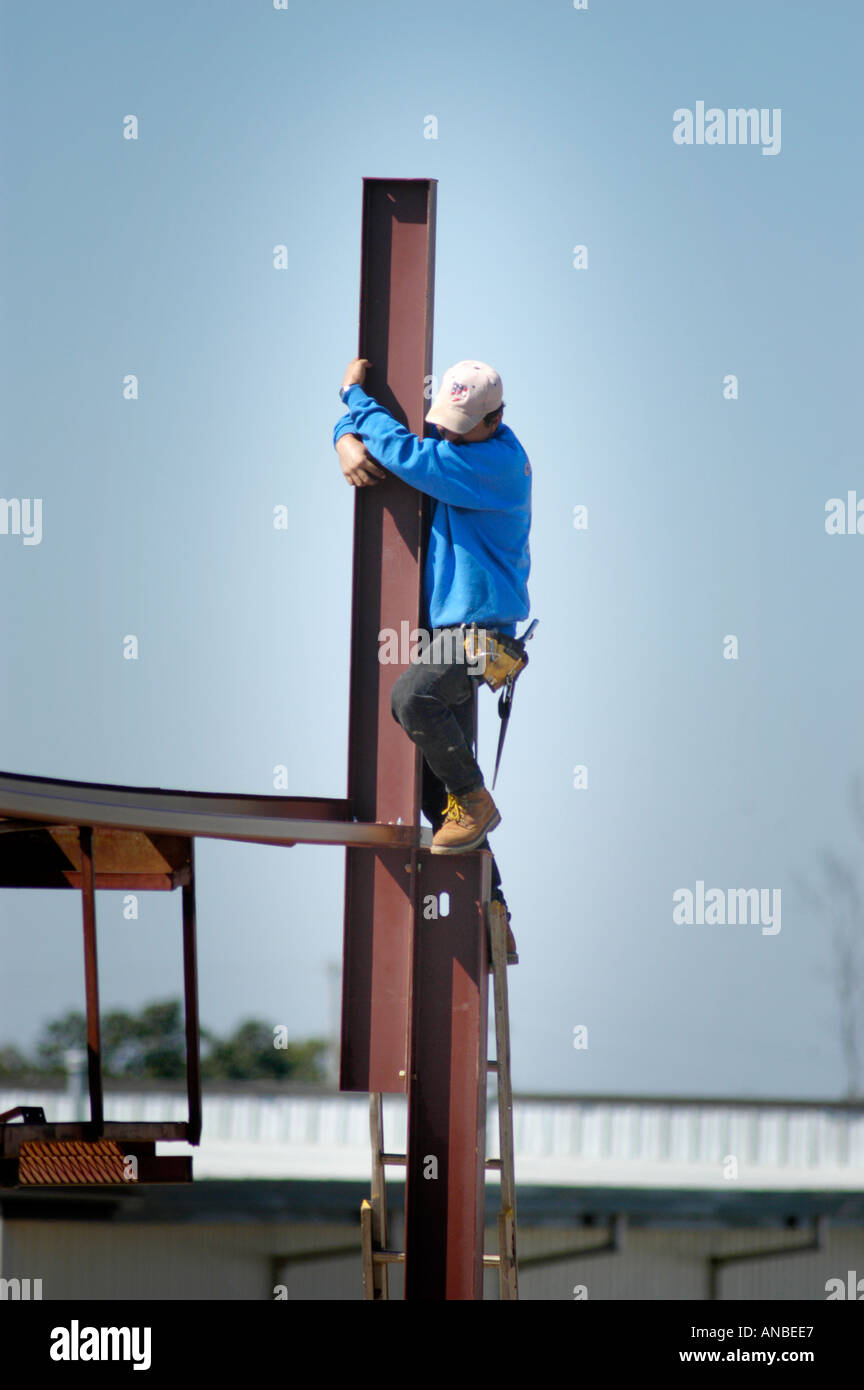 Prefab steel construction of building with worker assembling beams and ...