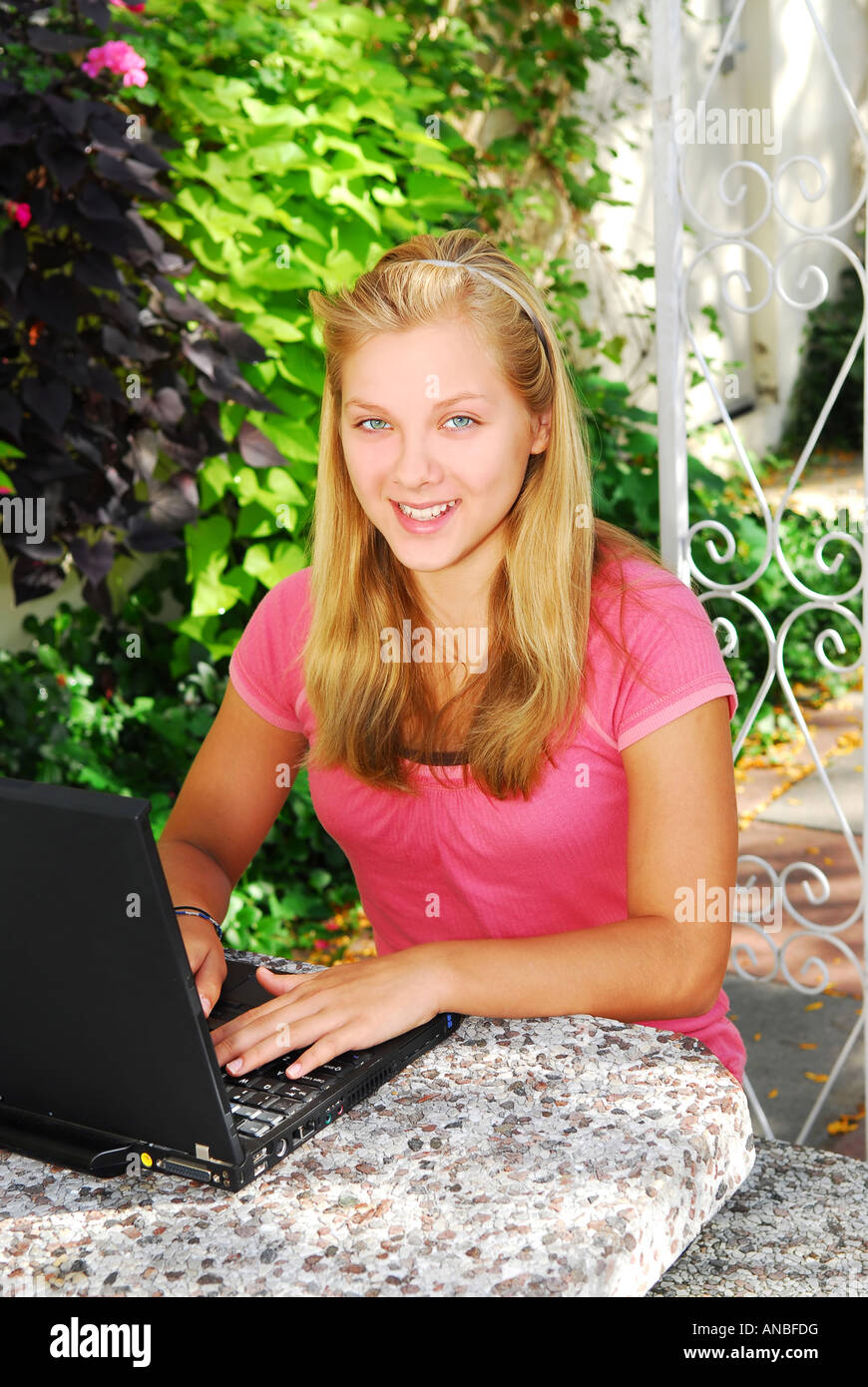 Smiling teenage girl typing on a portable computer outside Stock Photo ...