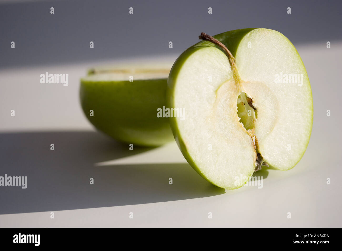 Apple cut in half strongly lit with shadows cast Stock Photo - Alamy