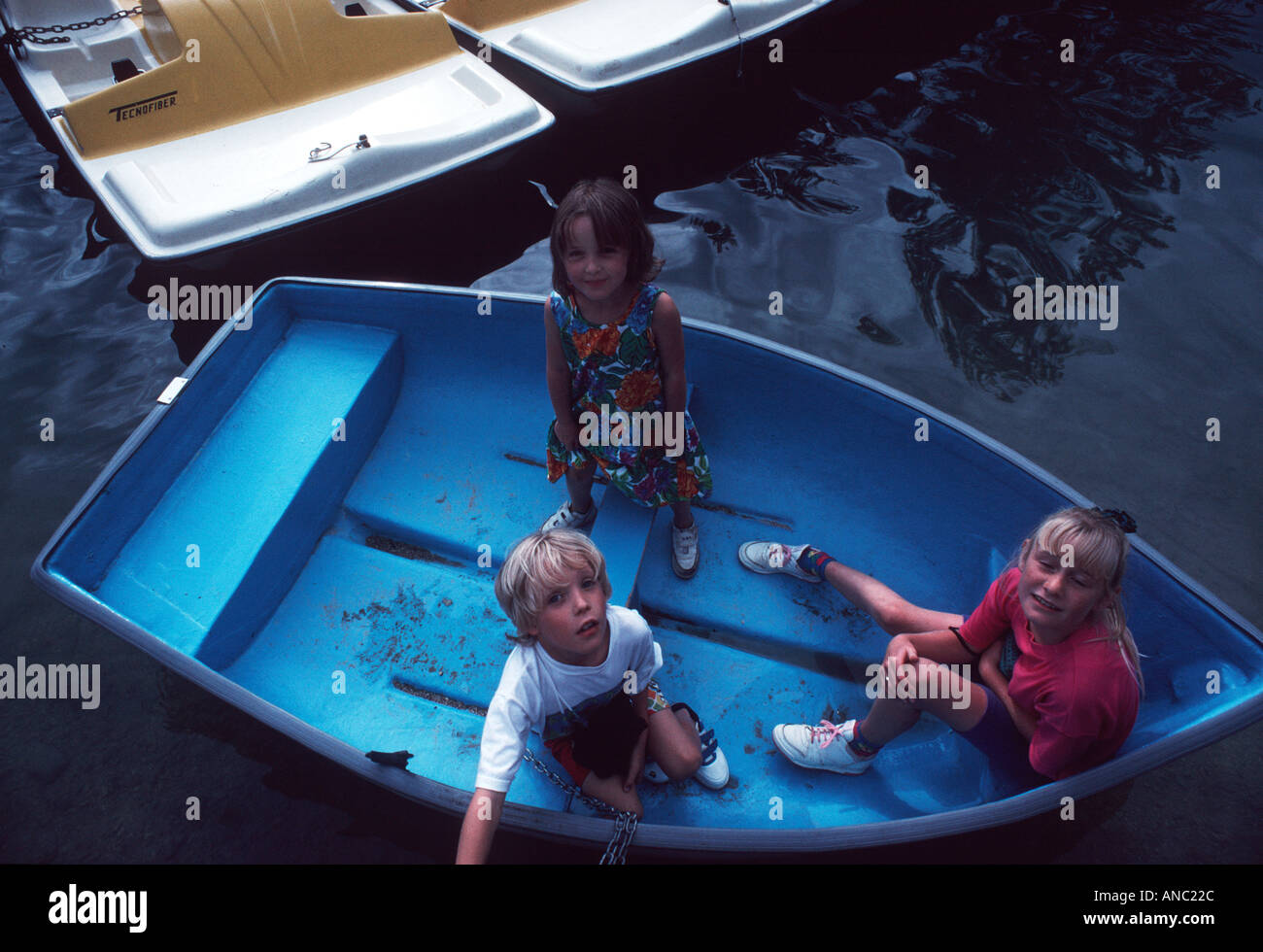Three young children two girls and a boy in a blue rowing boat viewed ...
