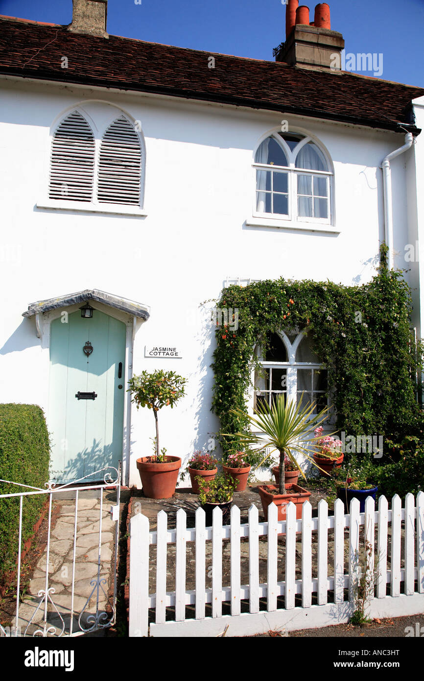 White picket fence in front of traditional white cottage with blue door ...