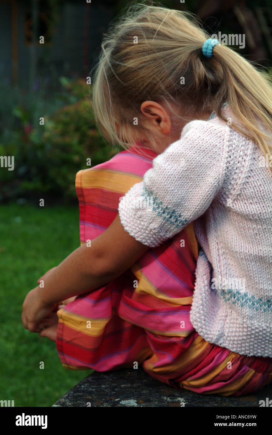 Back view of a little girl sitting curled up Stock Photo - Alamy