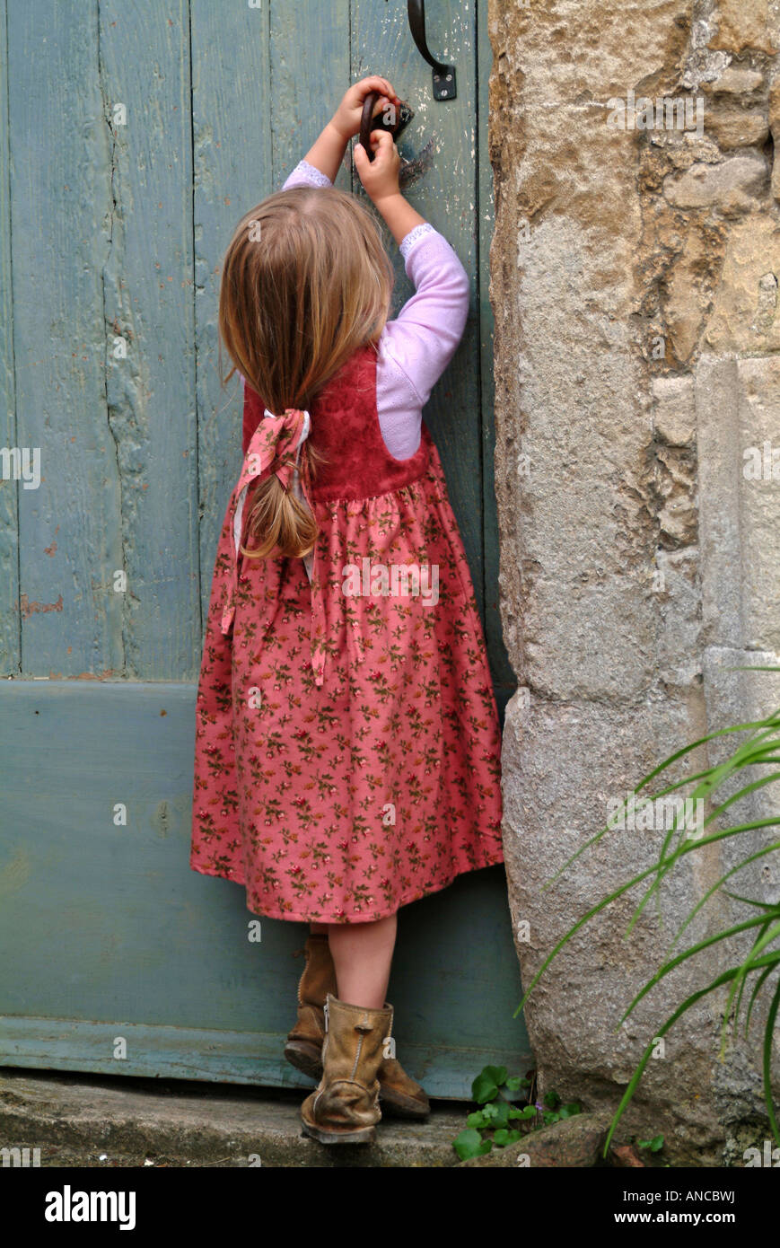 Little girl reaching up to open a door Stock Photo - Alamy