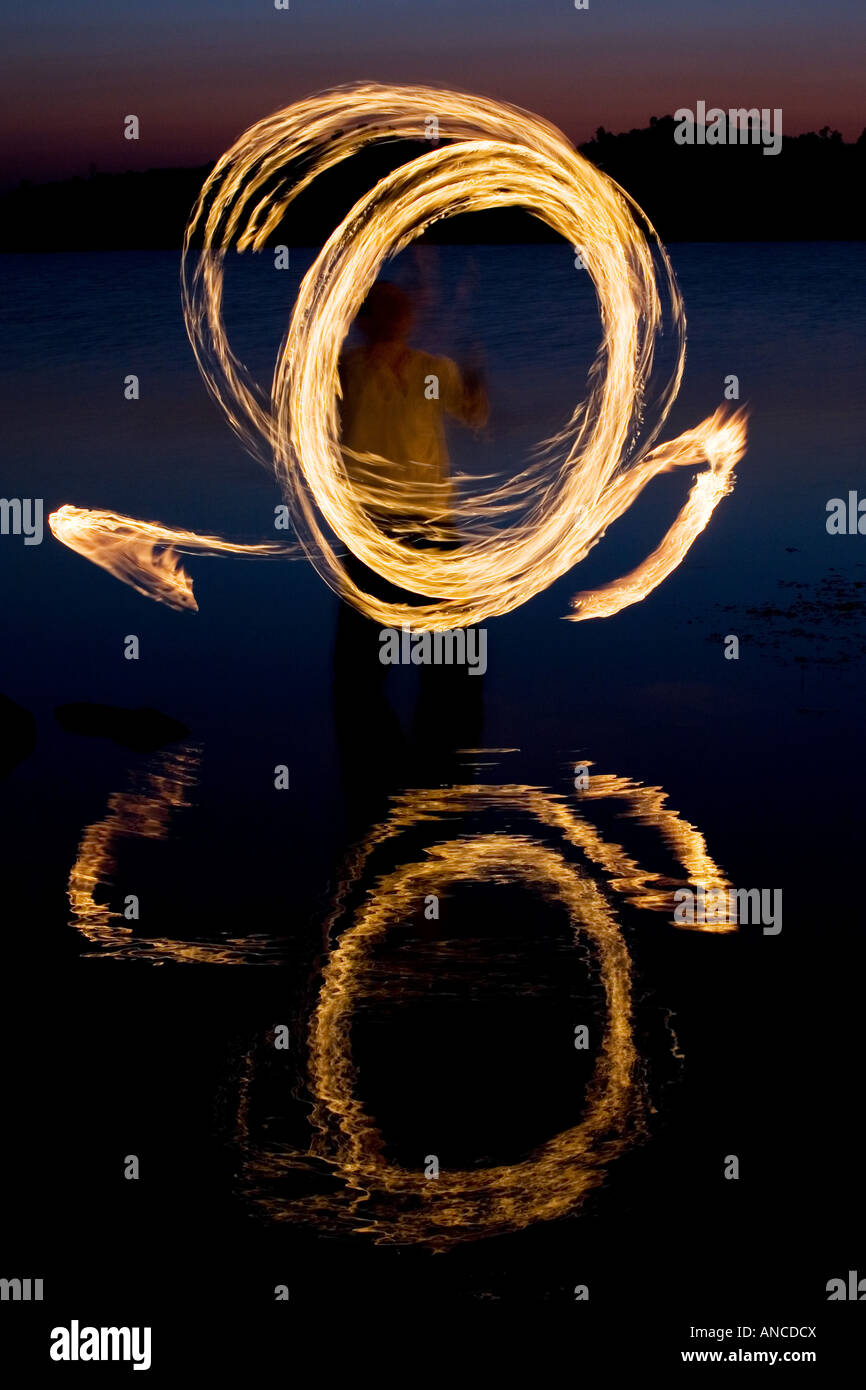 Man fire dancing on a rock in a lake in India Stock Photo - Alamy