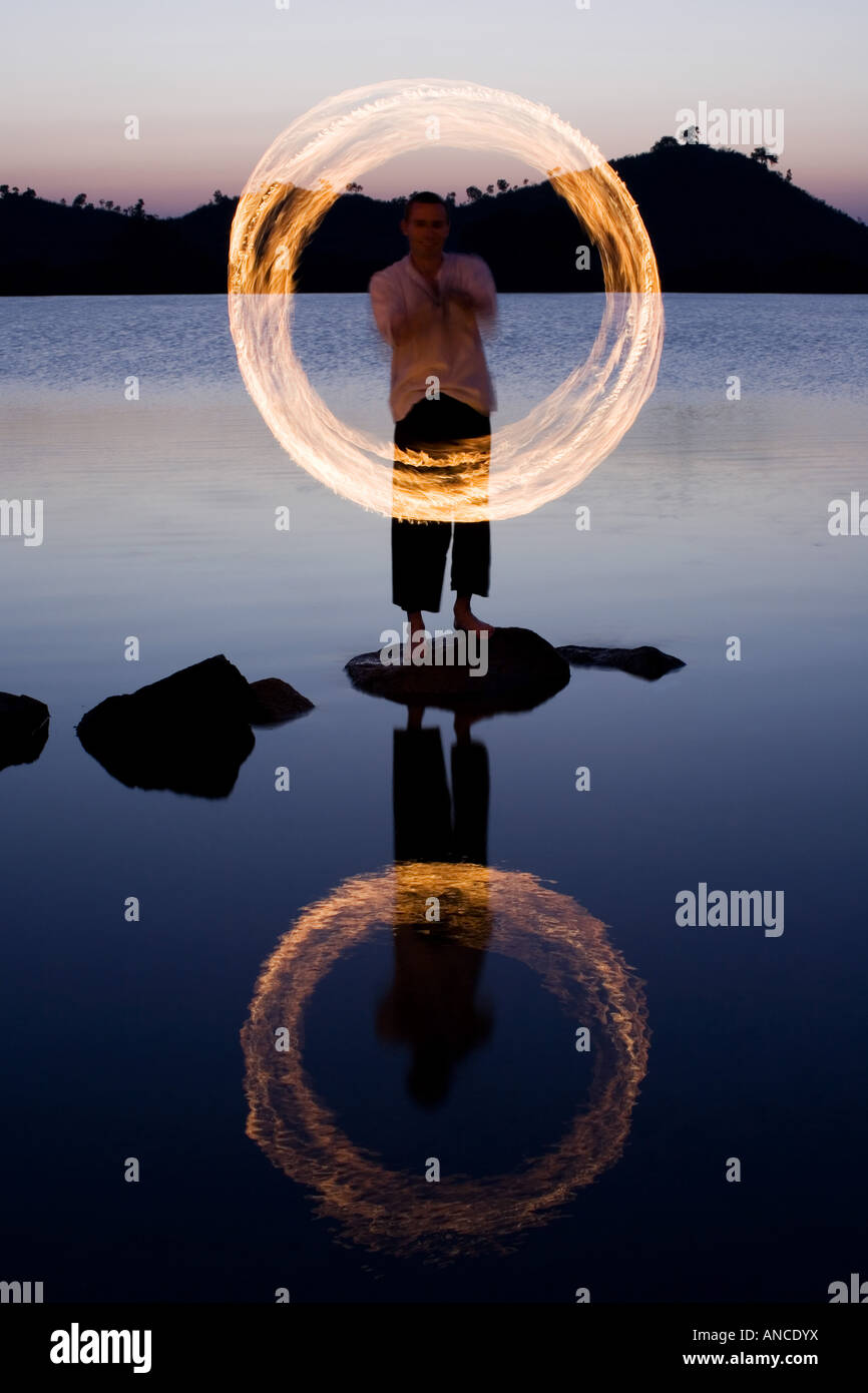 Man fire dancing on a rock in a lake in India Stock Photo - Alamy