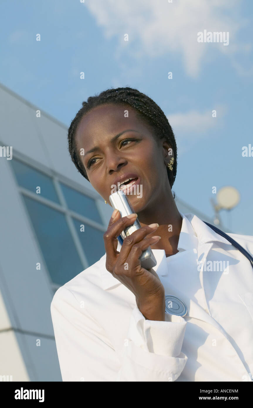 African female doctor speaking into mini tape recorder Stock Photo - Alamy