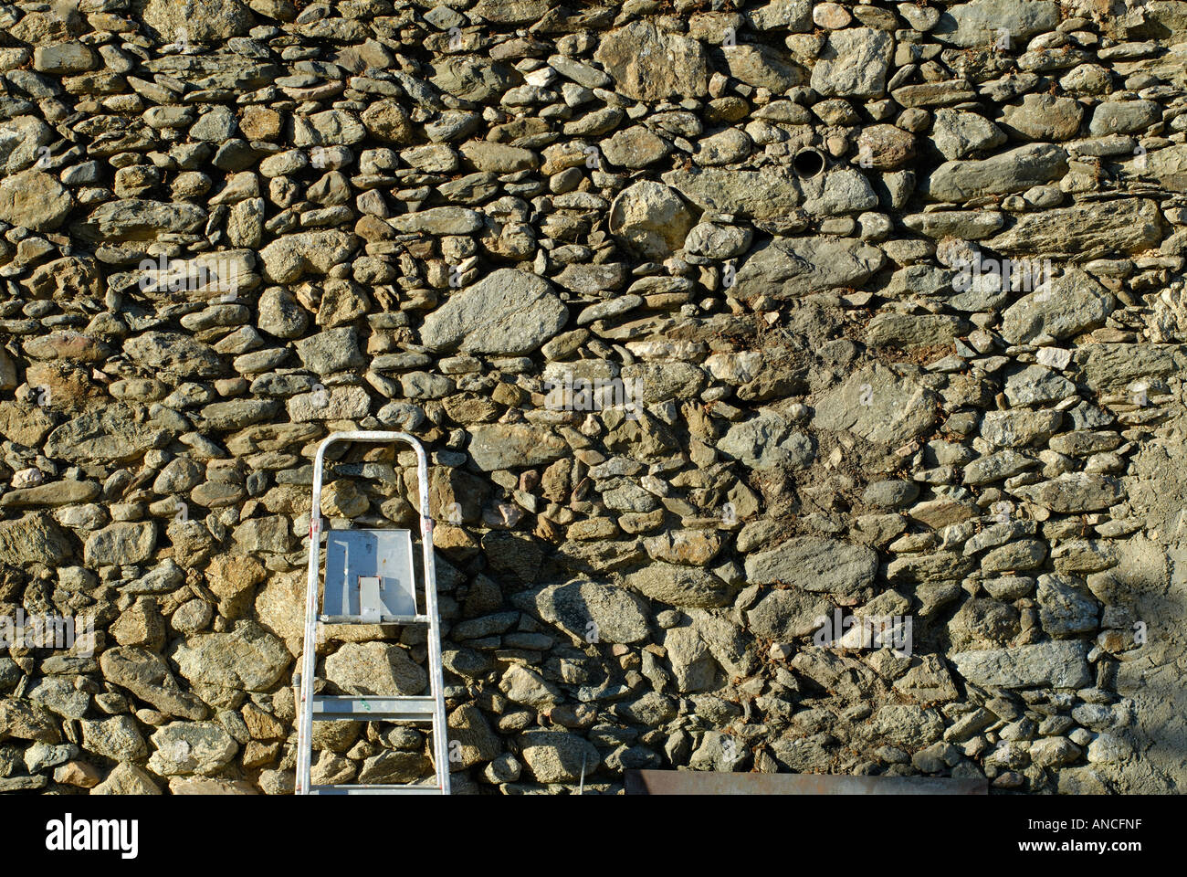 Metal ladder leaning against a stone wall Stock Photo - Alamy