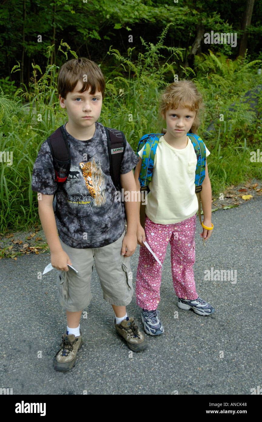 Grumpy children wait for the school bus for the first day of school ...
