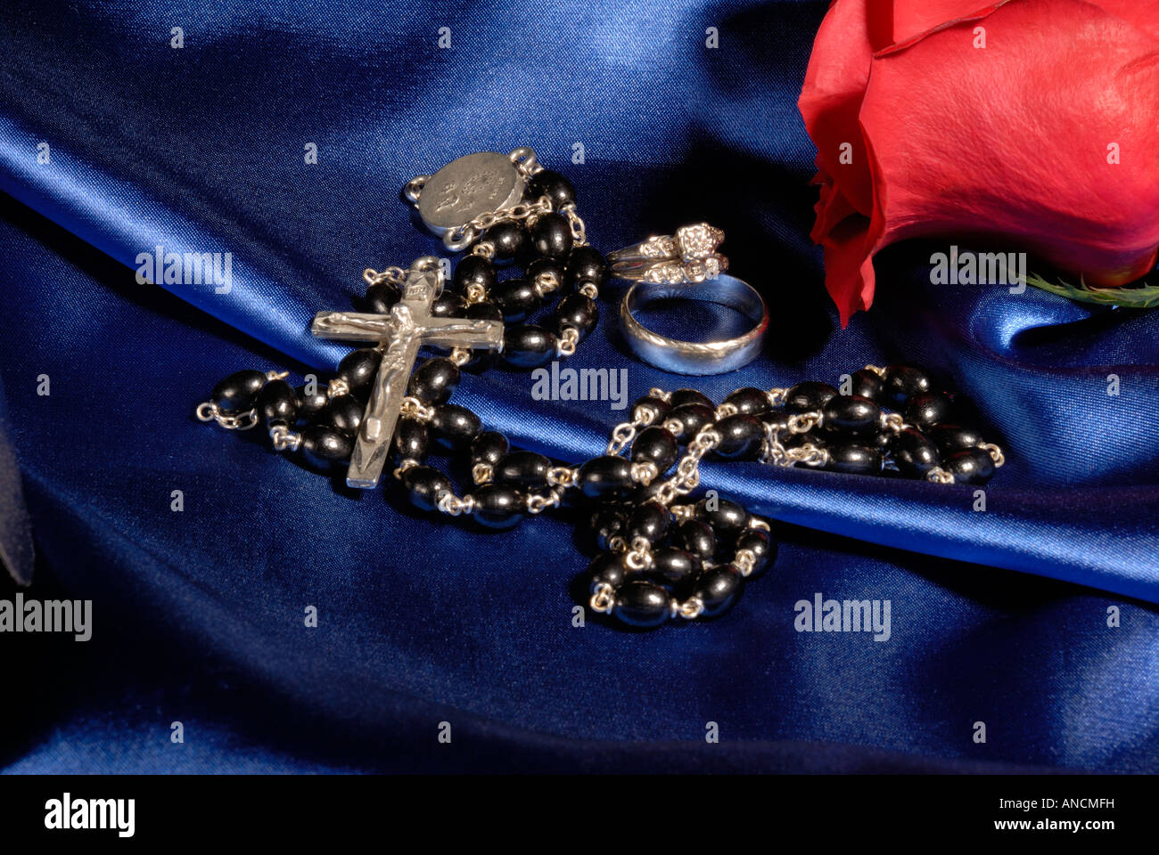 Wedding rings and rosary on blue satin with a rose Stock Photo - Alamy