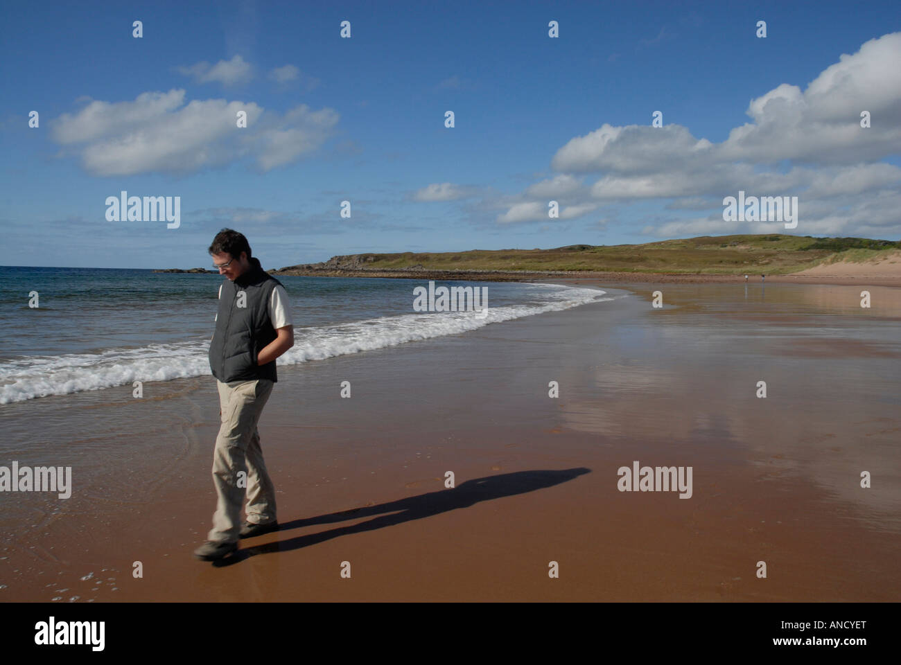 Man walking with his head down along a beach Stock Photo - Alamy
