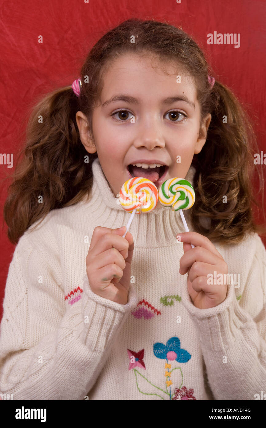 Greedy little girl with two lollipops Stock Photo - Alamy