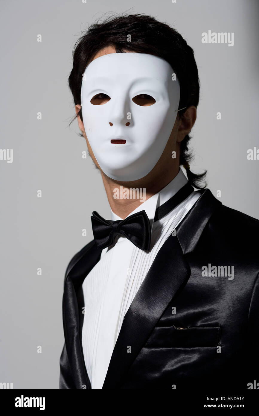 Man dressed in a ceremonial suit, wearing a white facial mask covering ...