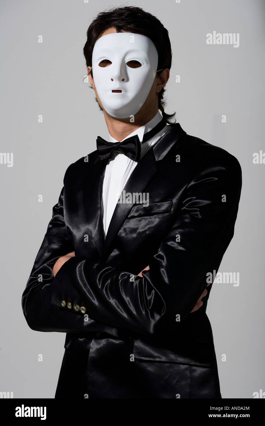 Man dressed in a ceremonial suit, wearing a white facial mask covering ...
