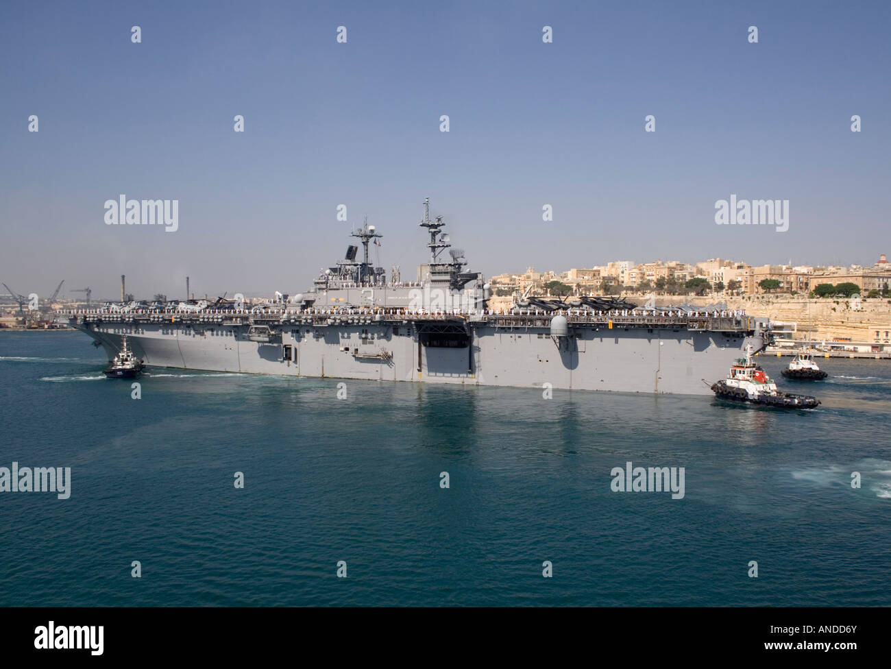 The amphibious assault ship USS Kearsarge is assisted by tugs as she ...