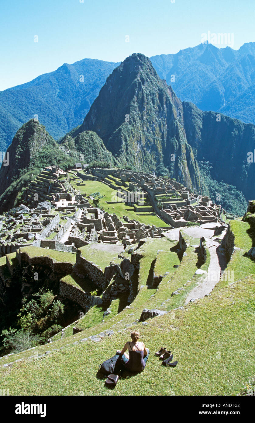 Machu Picchu Inca ruins, terraces, tourist sitting on terrace, and ...